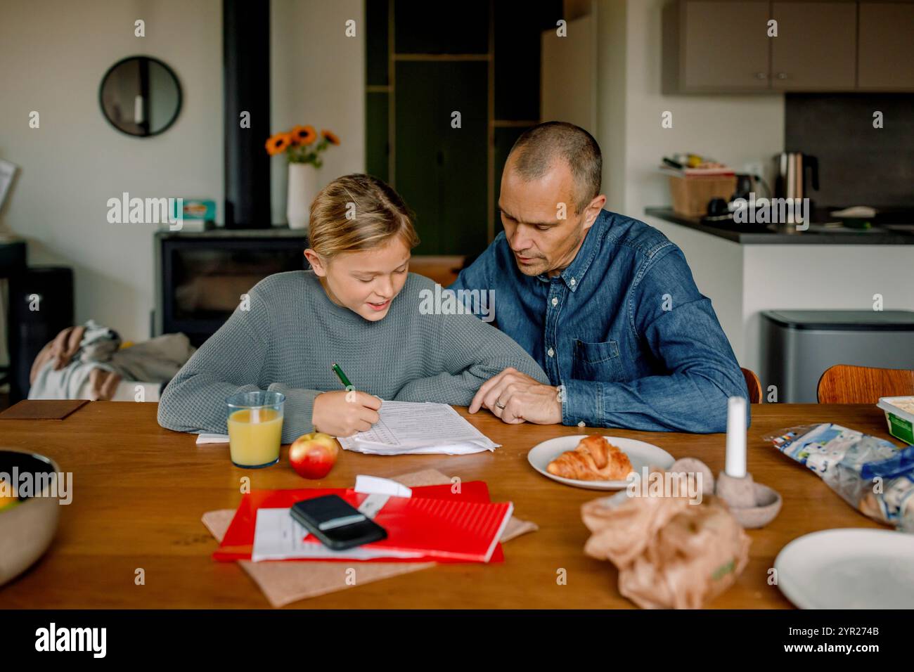 Father guiding son writing while sitting near table at home Stock Photo ...