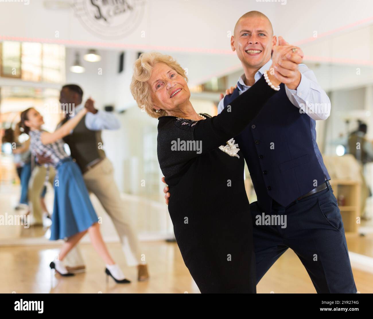 Elderly woman learning ballroom dancing movements in pair Stock Photo ...