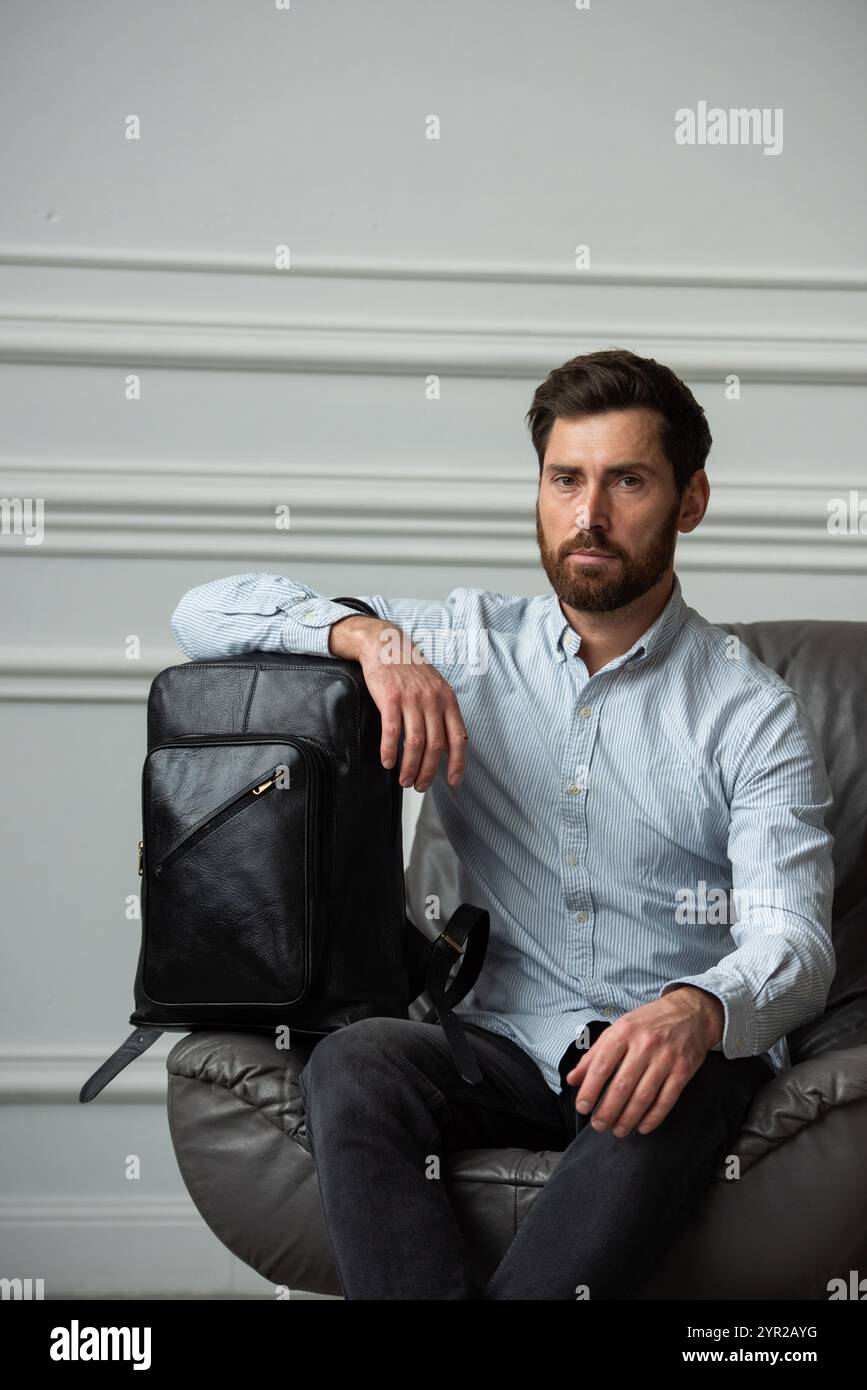 A man is comfortably sitting in a chair, resting with a leather ...