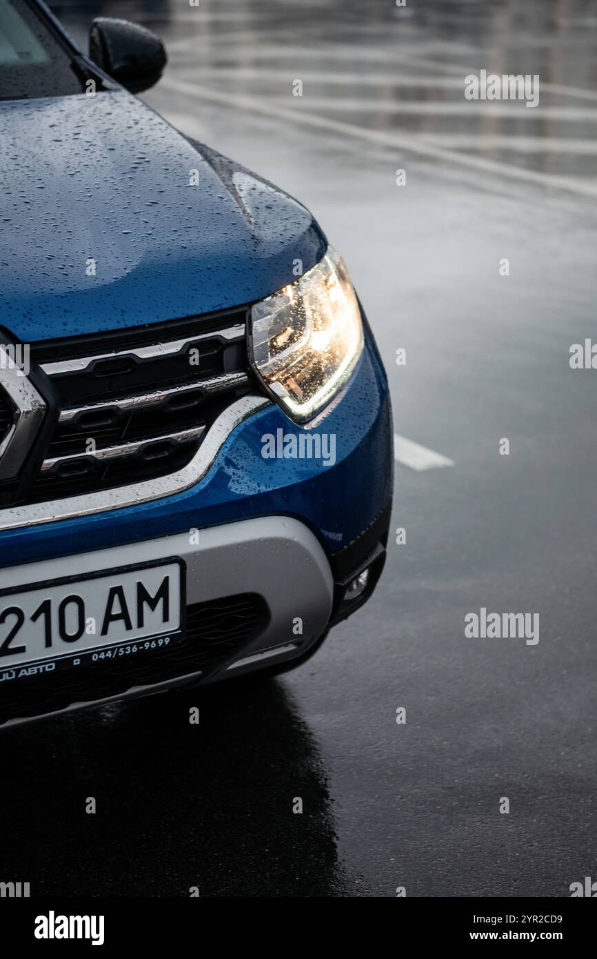 Front left corner of Renault Duster on rainy day. Headlight and bumper ...