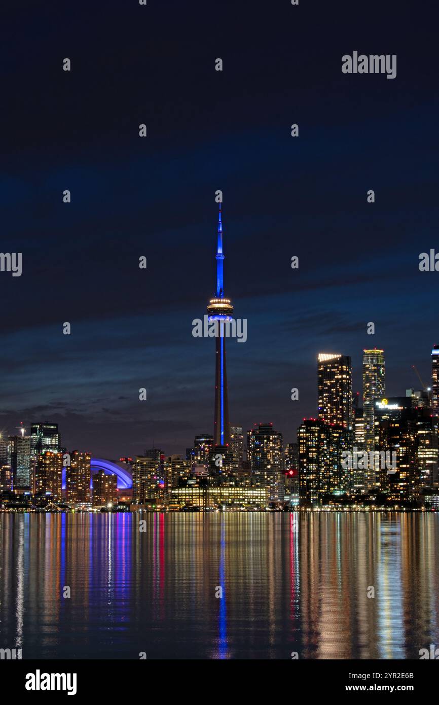 The CN Tower and Roger's centre illuminated at night amongst the ...