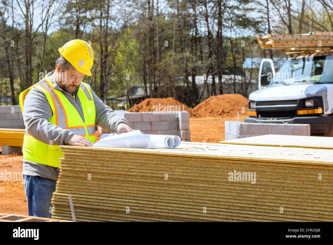 Construction supervisor worker in safety vest, hard hat studies ...