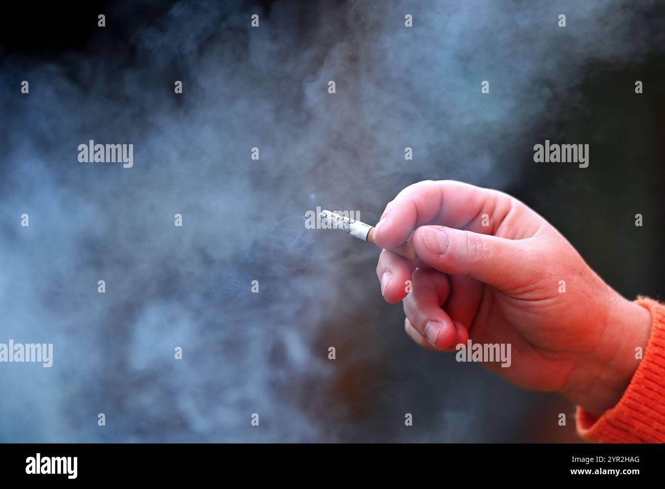 Symabolfoto Rauchen-qualmende Zigarette in einer Hand. Rauchen ...