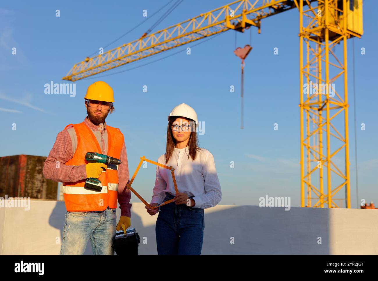Construction workers are posing at building site holding folding ruler ...