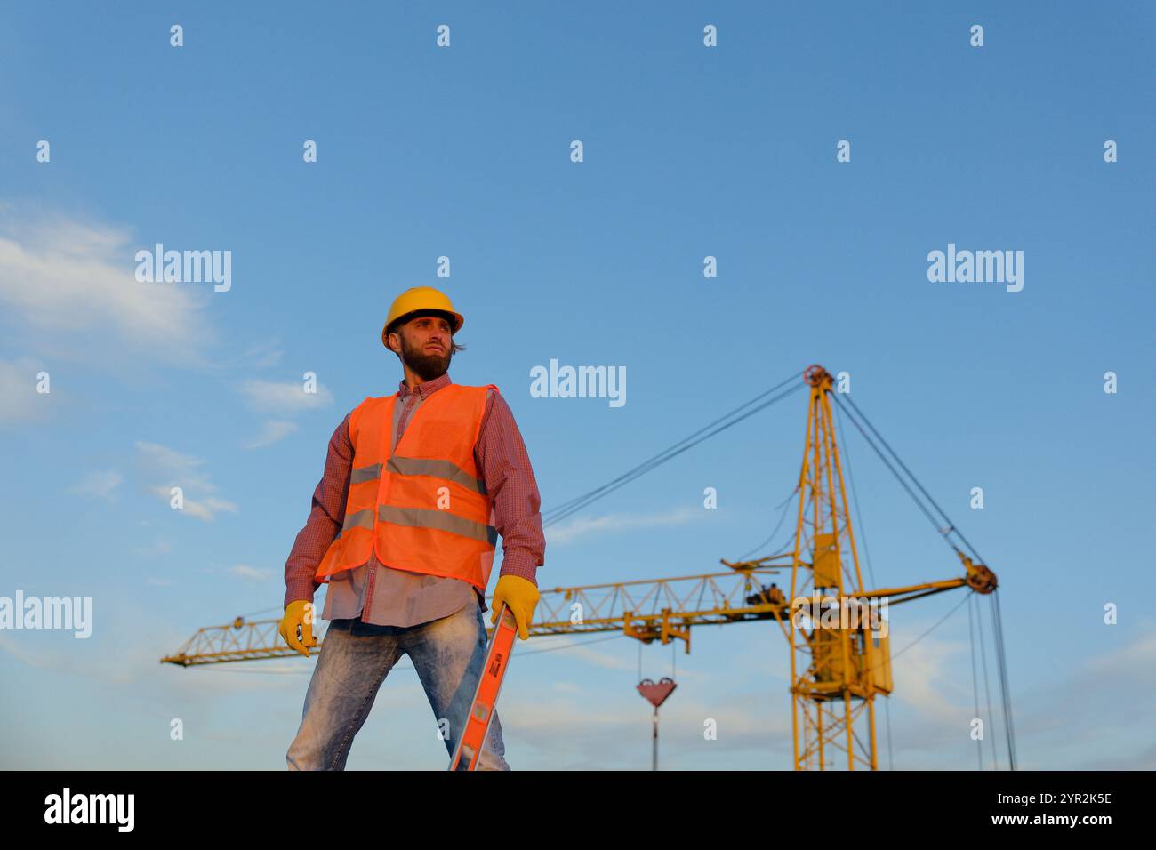 Construction worker holding spirit level tool at building site with ...