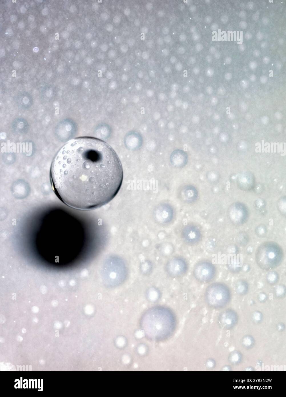 A clear sphere of water drop with a black shadow on it. The sphere is ...