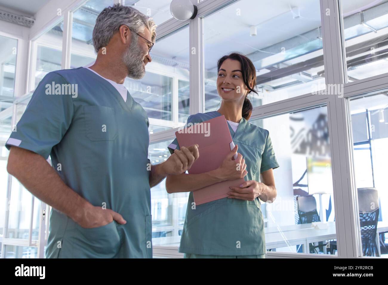 Two doctors walking in the clinic corridor and talking Stock Photo - Alamy