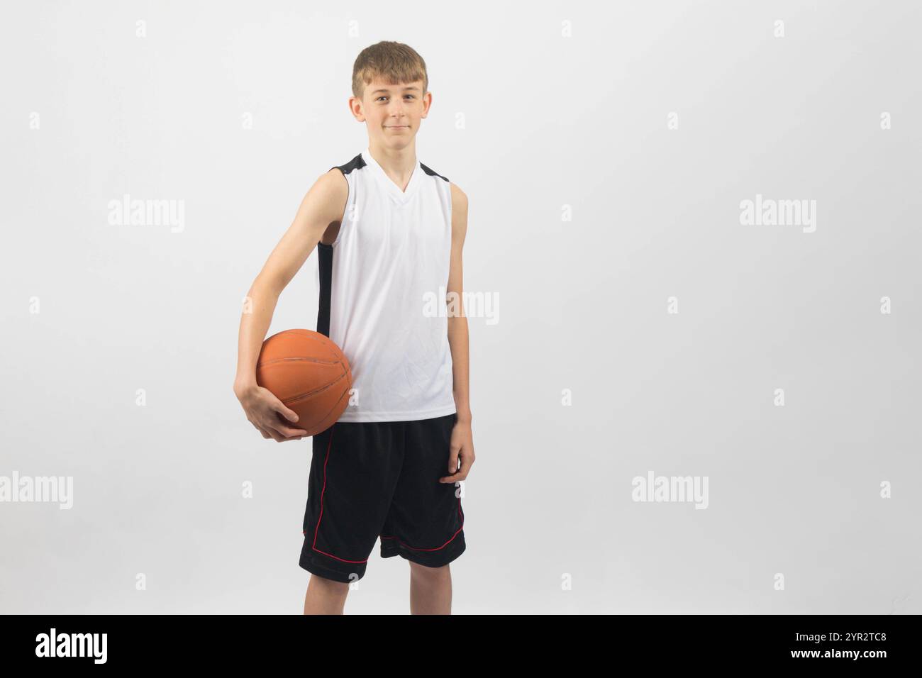 Fifteen year old teenage boy holding a basketball, studio shot against ...