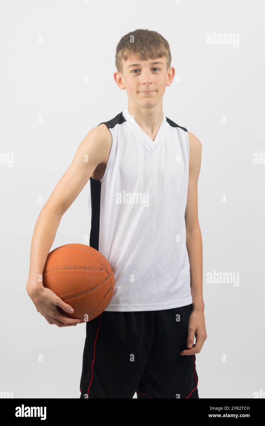 Fifteen year old teenage boy holding a basketball, studio shot against ...