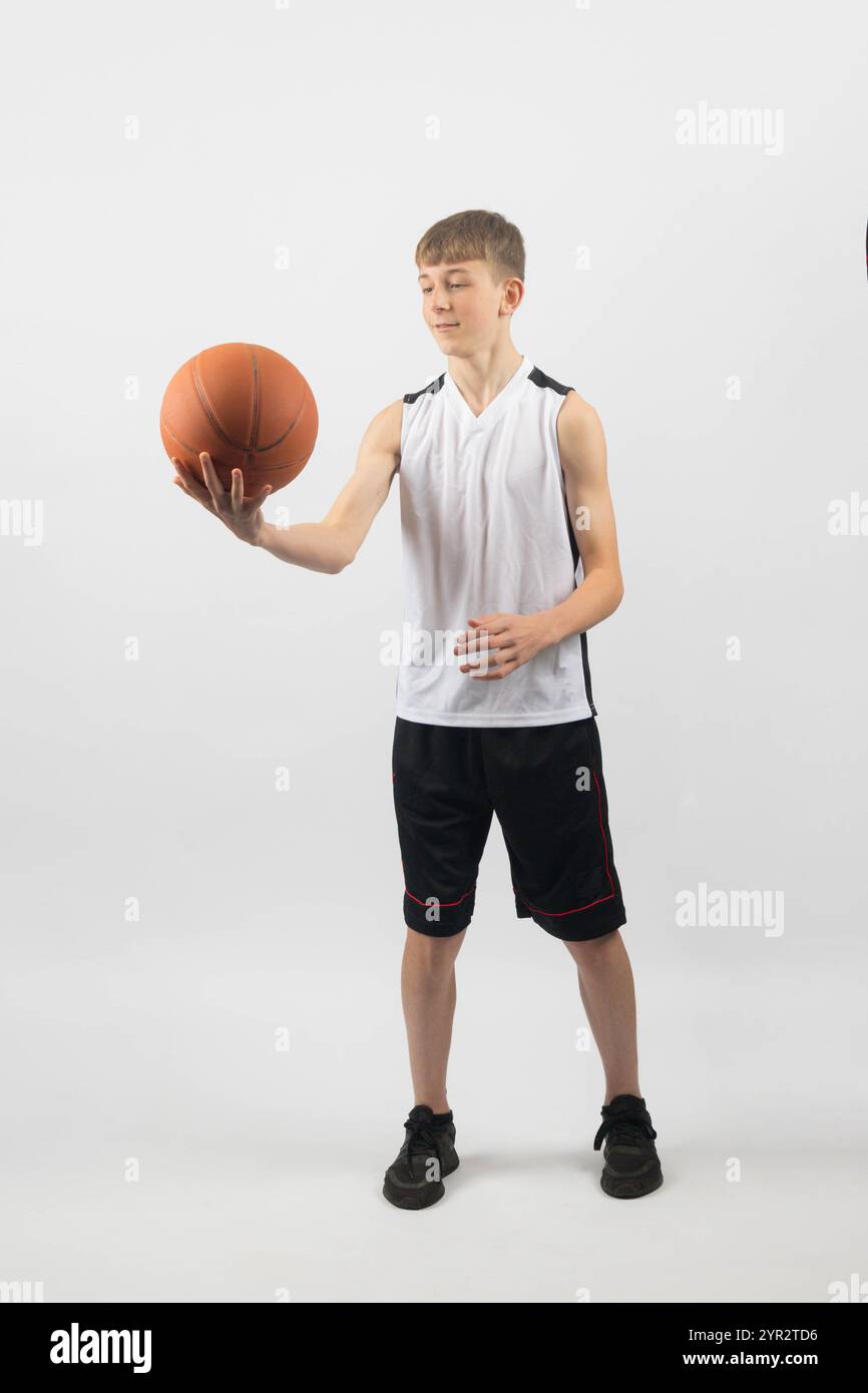 Fifteen year old teenage boy holding a basketball, studio shot against ...
