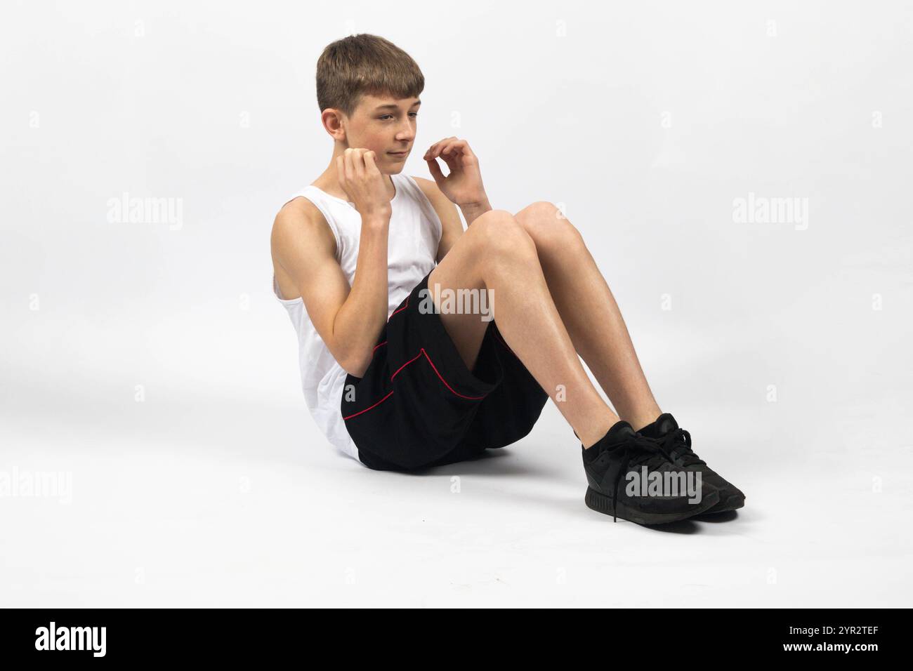 Fifteen year old teenage boy doing sit ups, studio shot against a white ...
