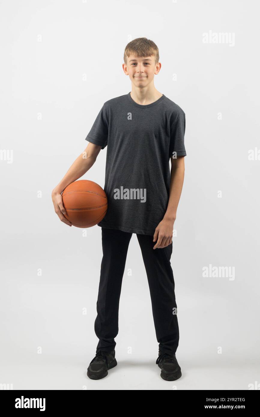 Fifteen year old teenage boy holding a basketball, studio shot against ...