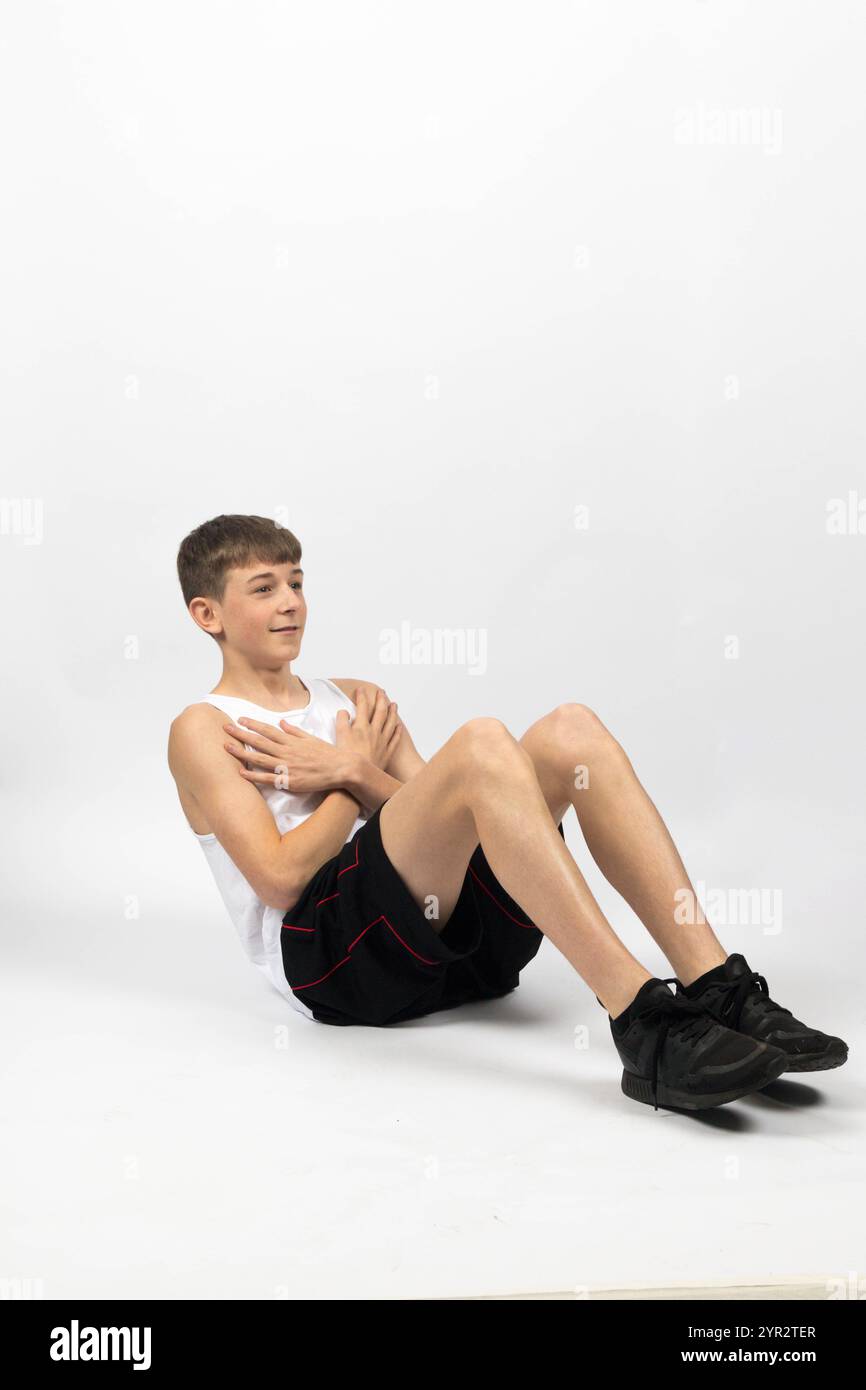 Fifteen year old teenage boy doing sit ups, studio shot against a white ...