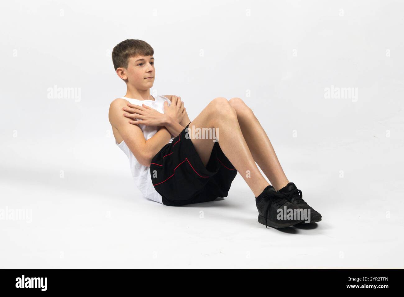 Fifteen year old teenage boy doing sit ups, studio shot against a white ...