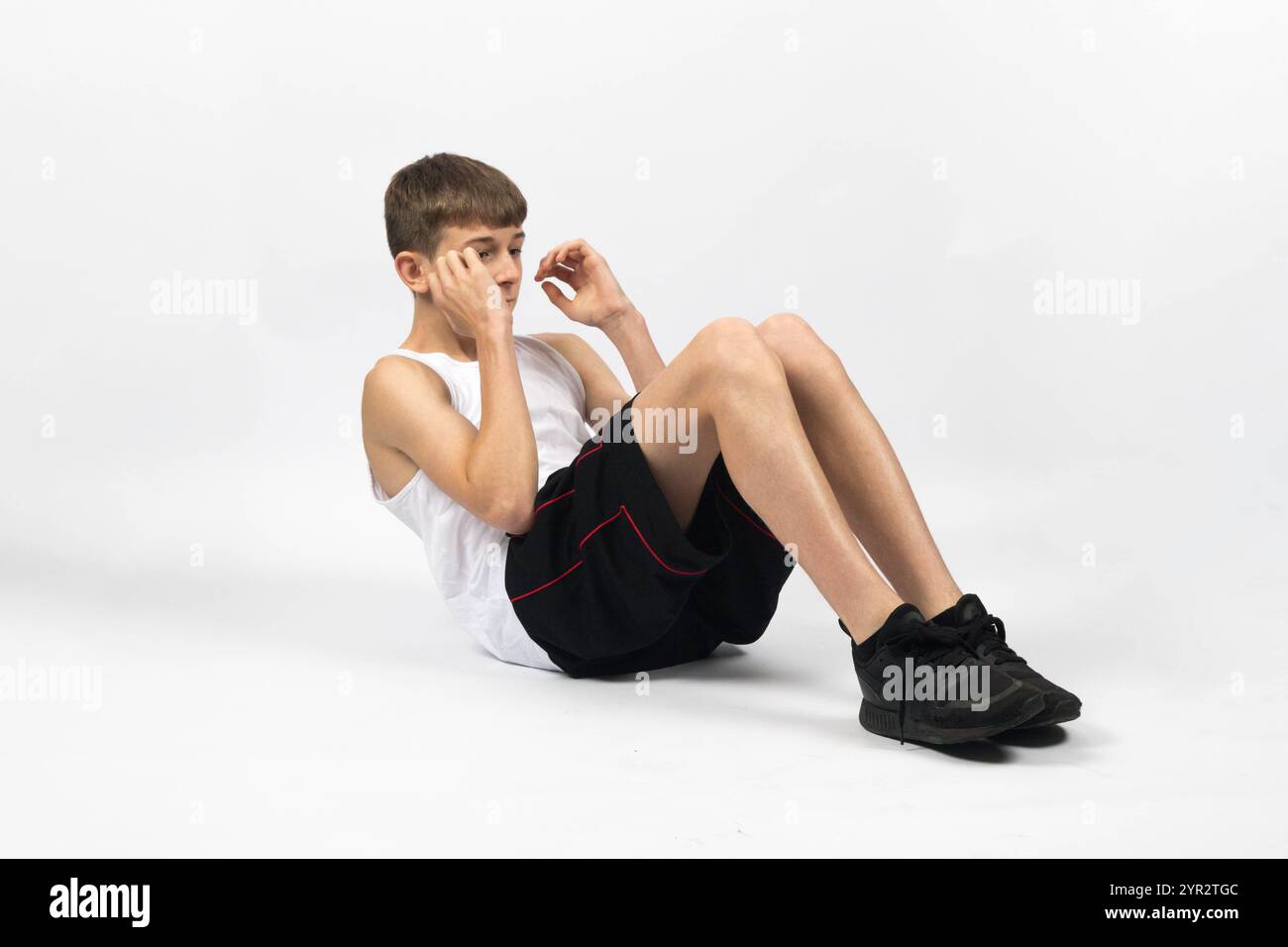 Fifteen year old teenage boy doing sit ups, studio shot against a white ...