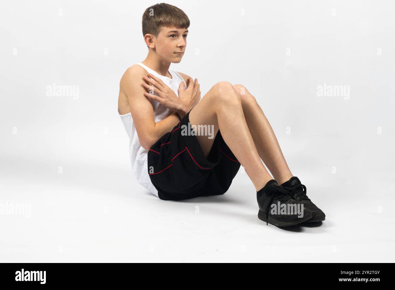 Fifteen year old teenage boy doing sit ups, studio shot against a white ...