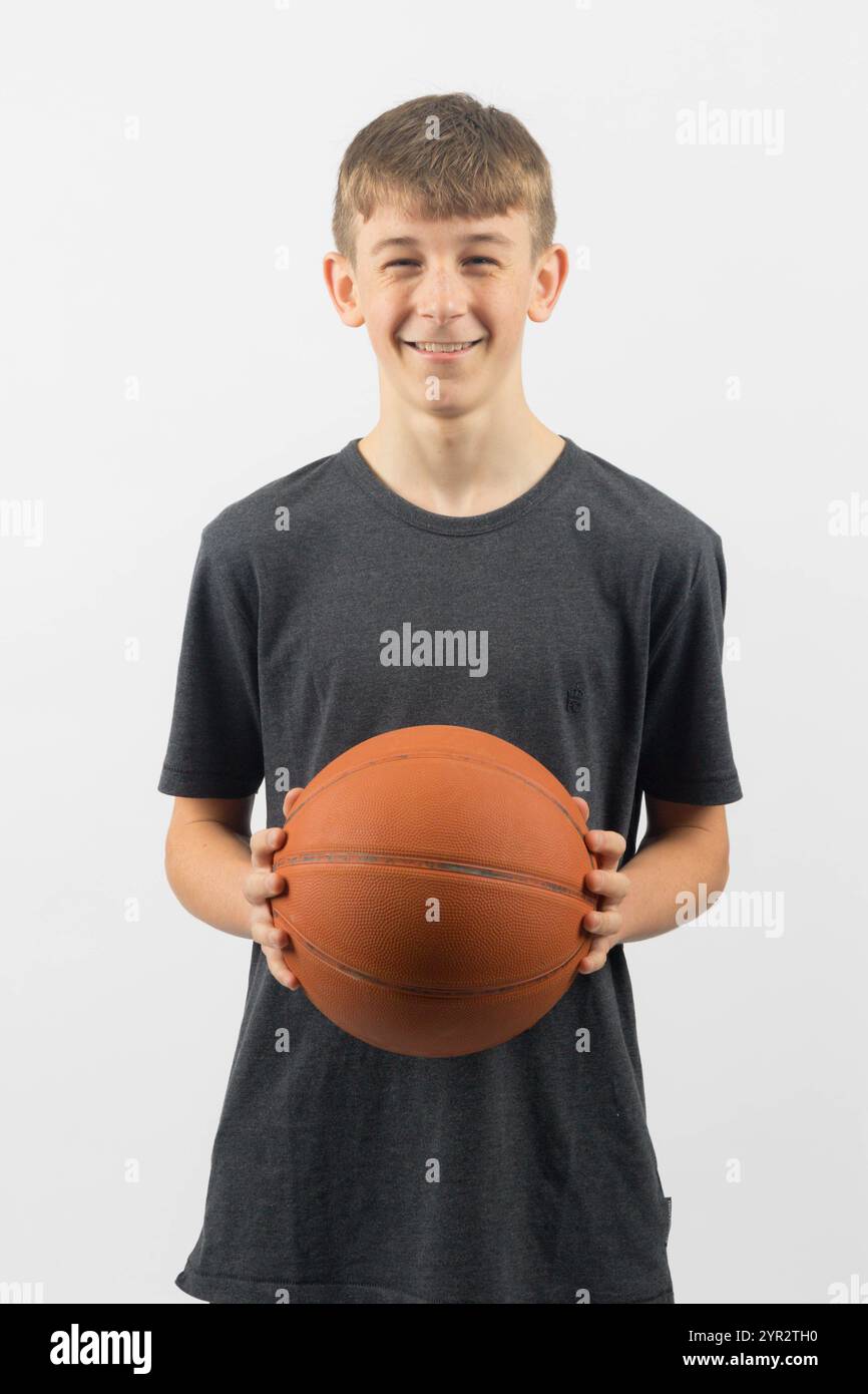Fifteen year old teenage boy holding a basketball, studio shot against ...
