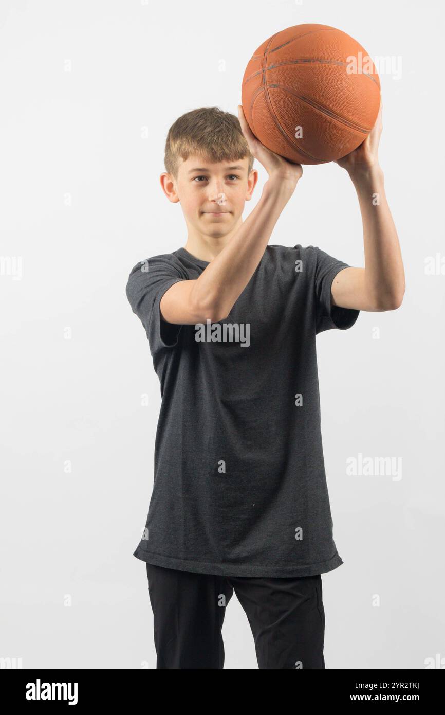 Fifteen year old teenage boy about to shoot a basketball, studio shot ...