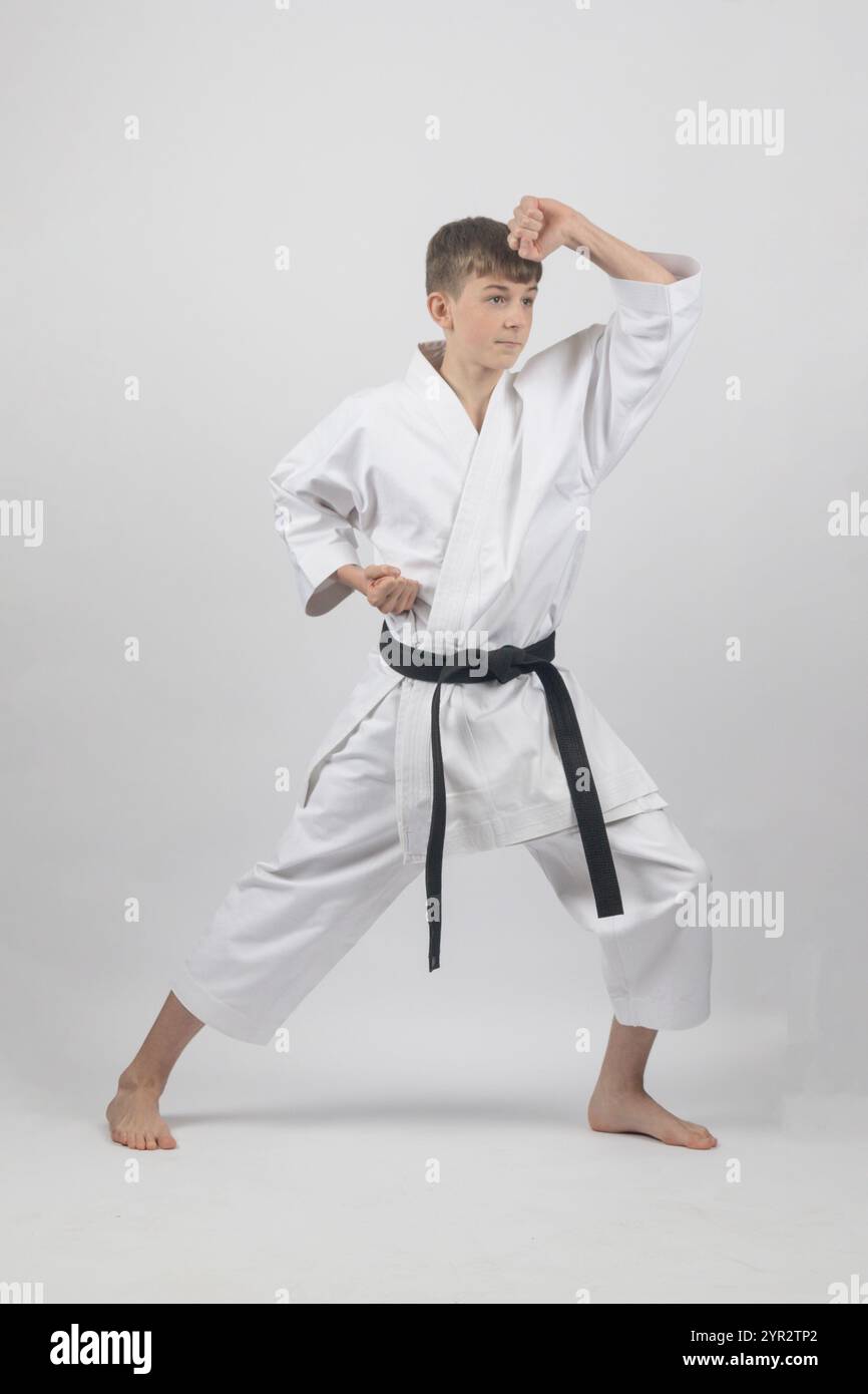 Fifteen year old male teenage karate black belt in long stance doing a ...
