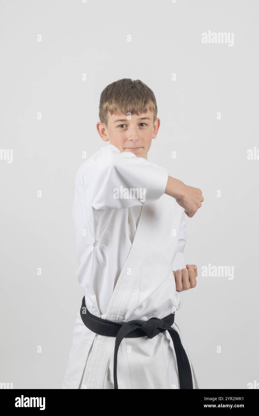 Fifteen year old male teenage karate black belt performing a side back ...