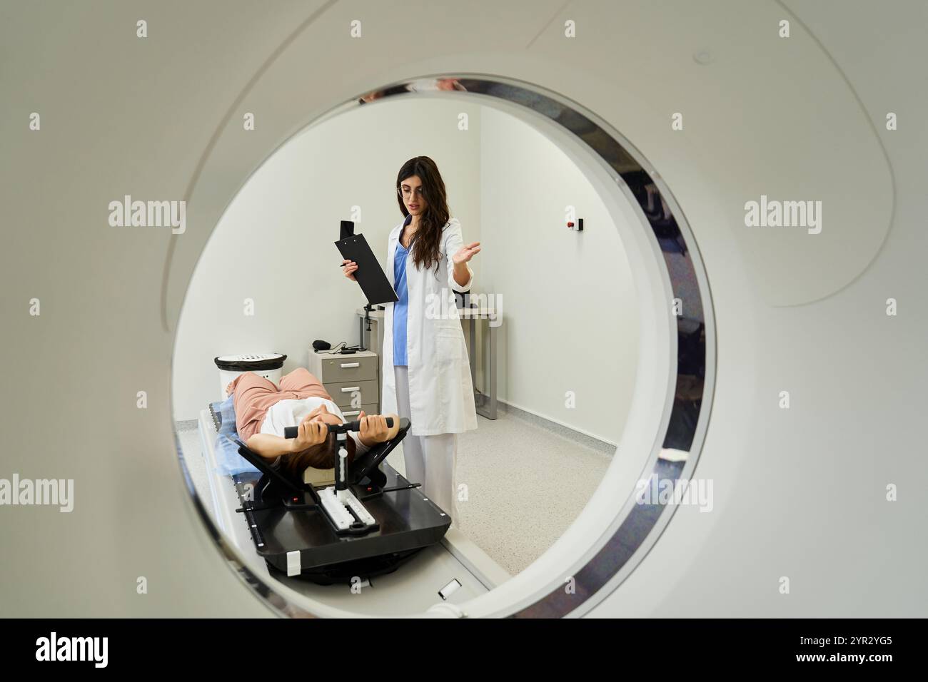 A female doctor instructs a patient during an MRI scan in a radiology ...
