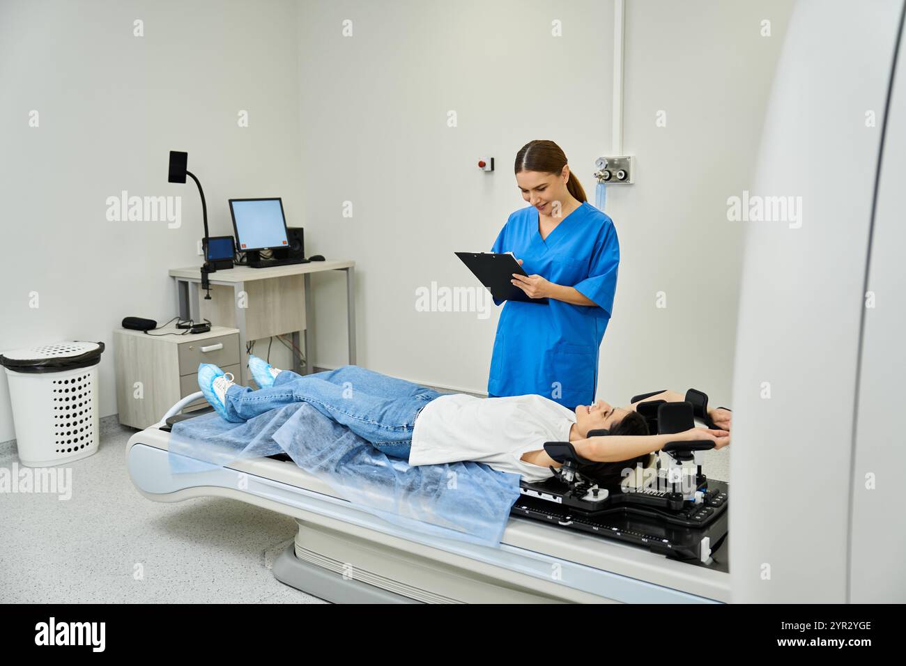 A doctor in a lab coat oversees a patient undergoing an MRI scan in a ...
