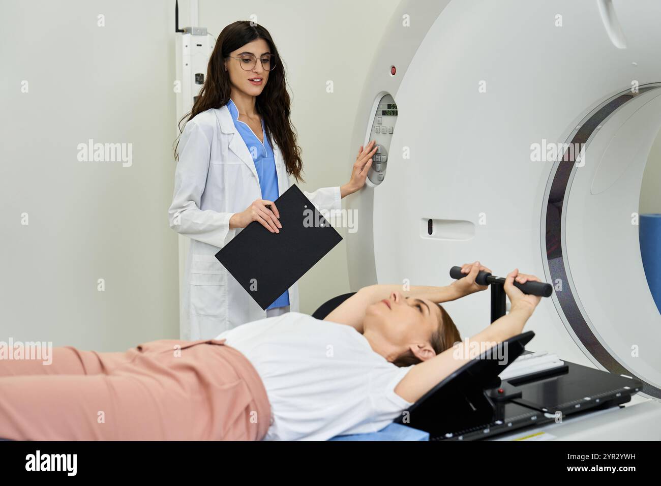 A woman in a lab coat guides a patient undergoing an MRI procedure in a ...