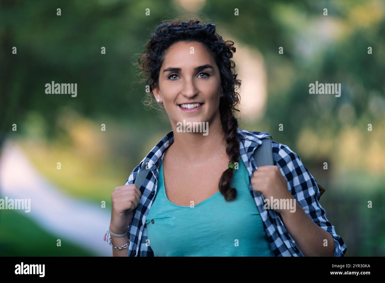 Young university student happily strolling through a lush campus park ...
