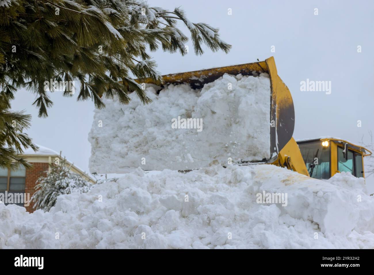 Snow removal process in neighborhood with bulldozer moving large mounds ...