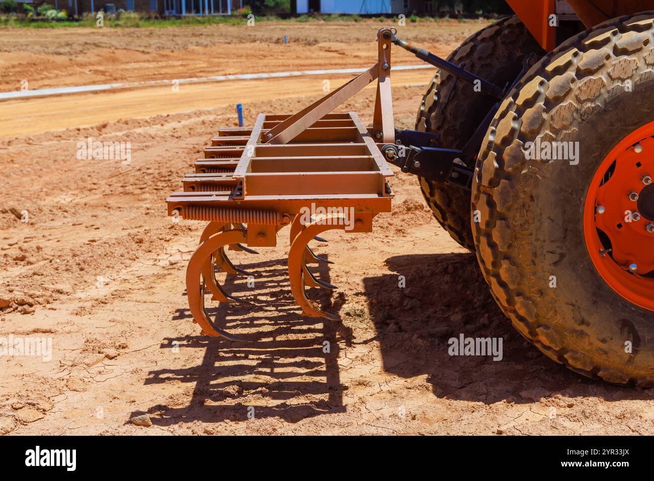 Tractor with tilling attachment is working on construction site, preparing dirt for future ...