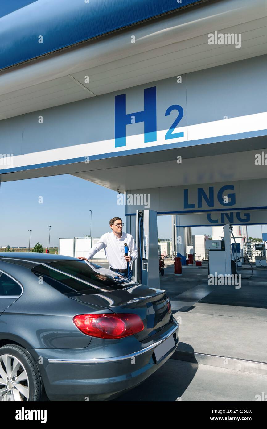 Man holds a hydrogen fueling nozzle on a hydrogen filling station ...