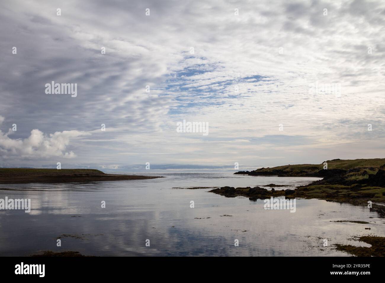 The calm sea in Iceland reflecting the clouds that seamlessly merge ...