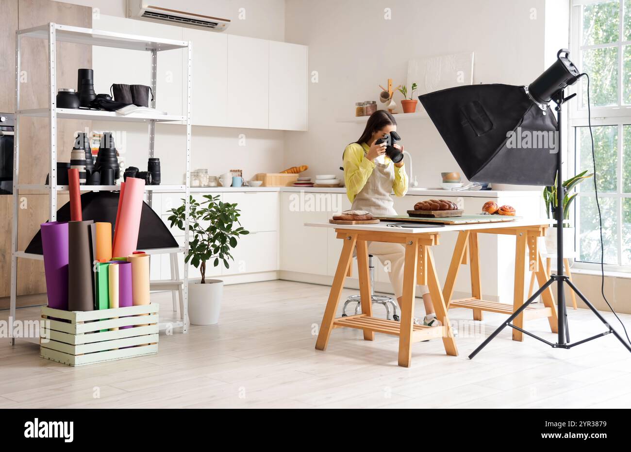 Young female photographer taking picture of food in modern kitchen ...