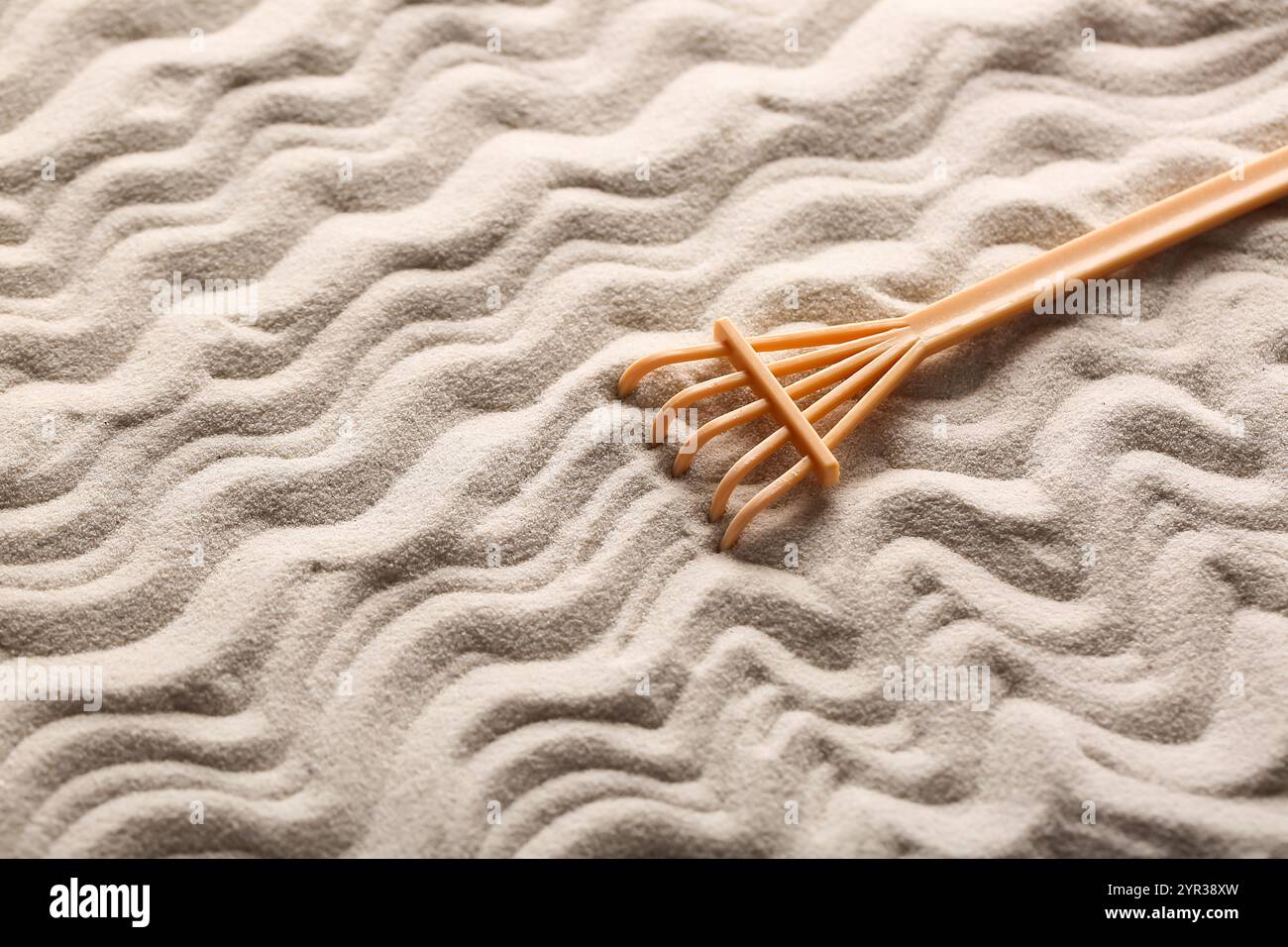 Small rake on light sand with lines in Japanese rock garden. Zen ...