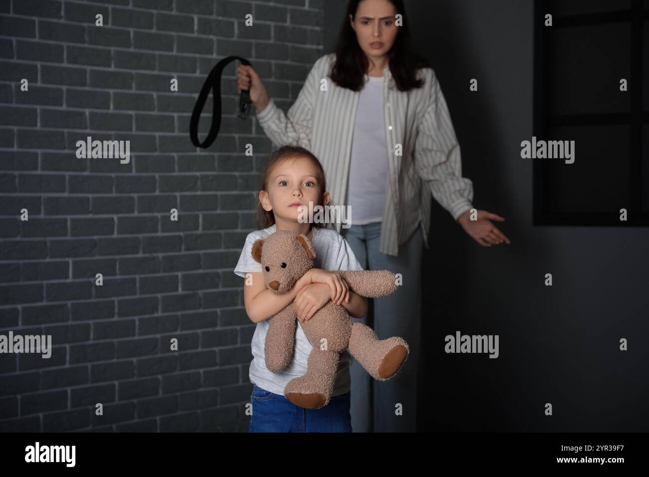 Scared little girl with toy bear and her angry mother at home. Domestic ...