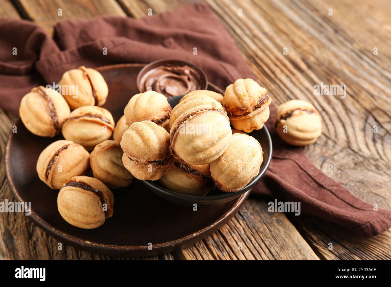 Plate and bowl of sweet walnut shaped cookies with boiled condensed ...