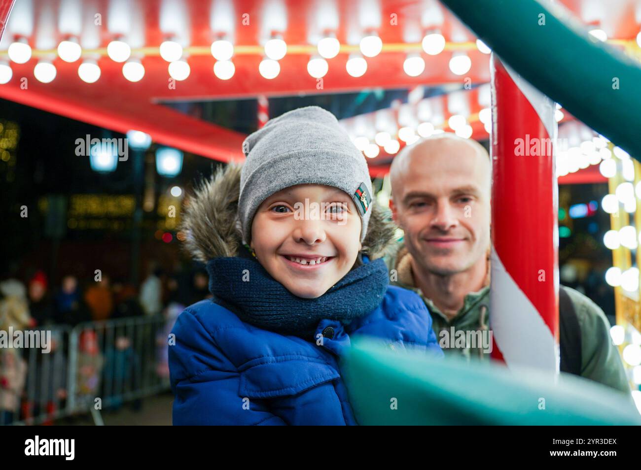 Family enjoying a carousel ride at a Christmas market on a winter night ...