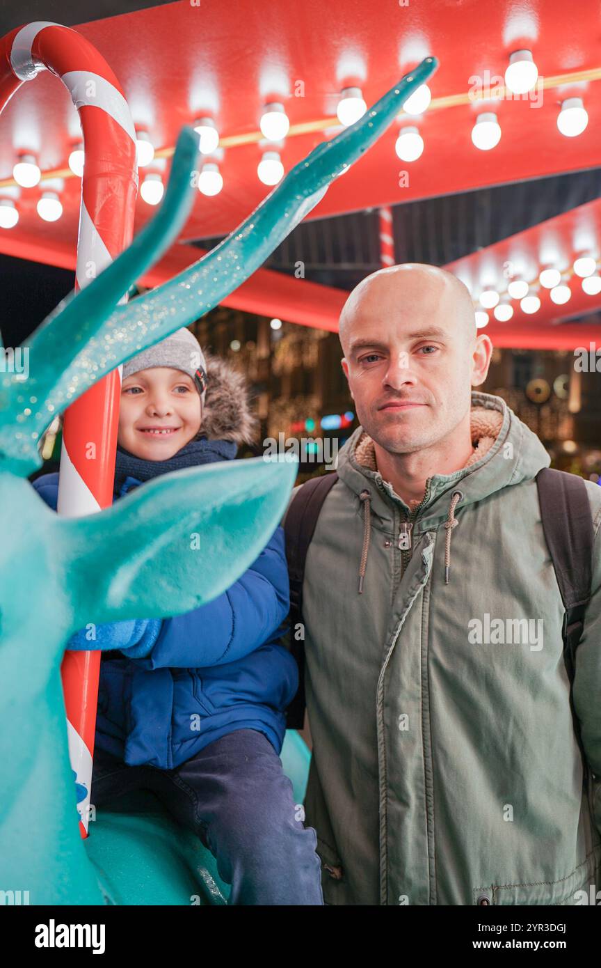 Family enjoying a carousel ride at a Christmas market on a winter night ...