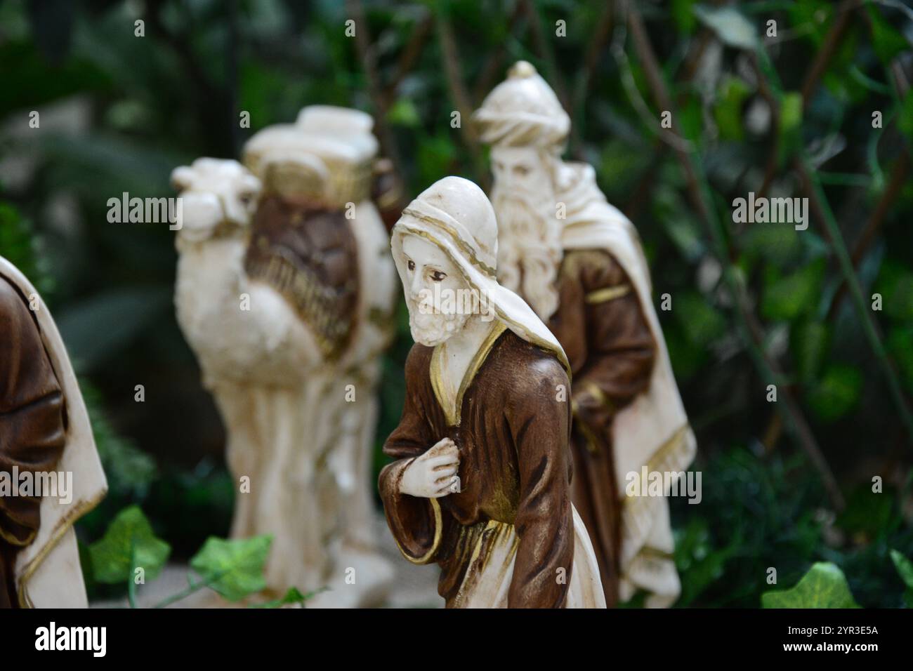 Figures of a nativity scene with a camel in the background on a blurred ...