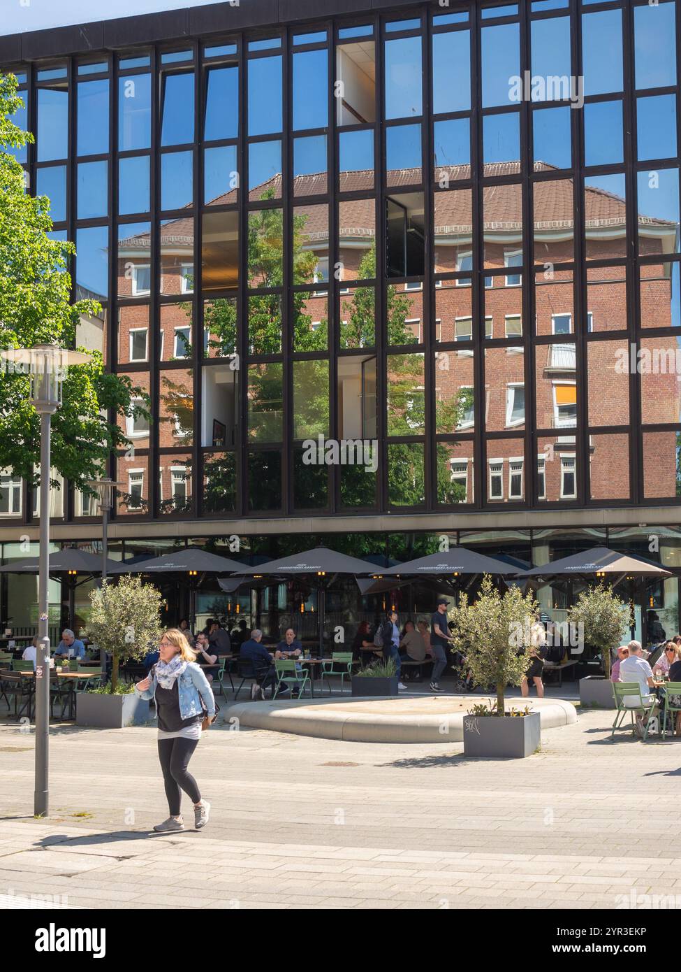 A tall mirror glass building reflects a brick building in its glass ...