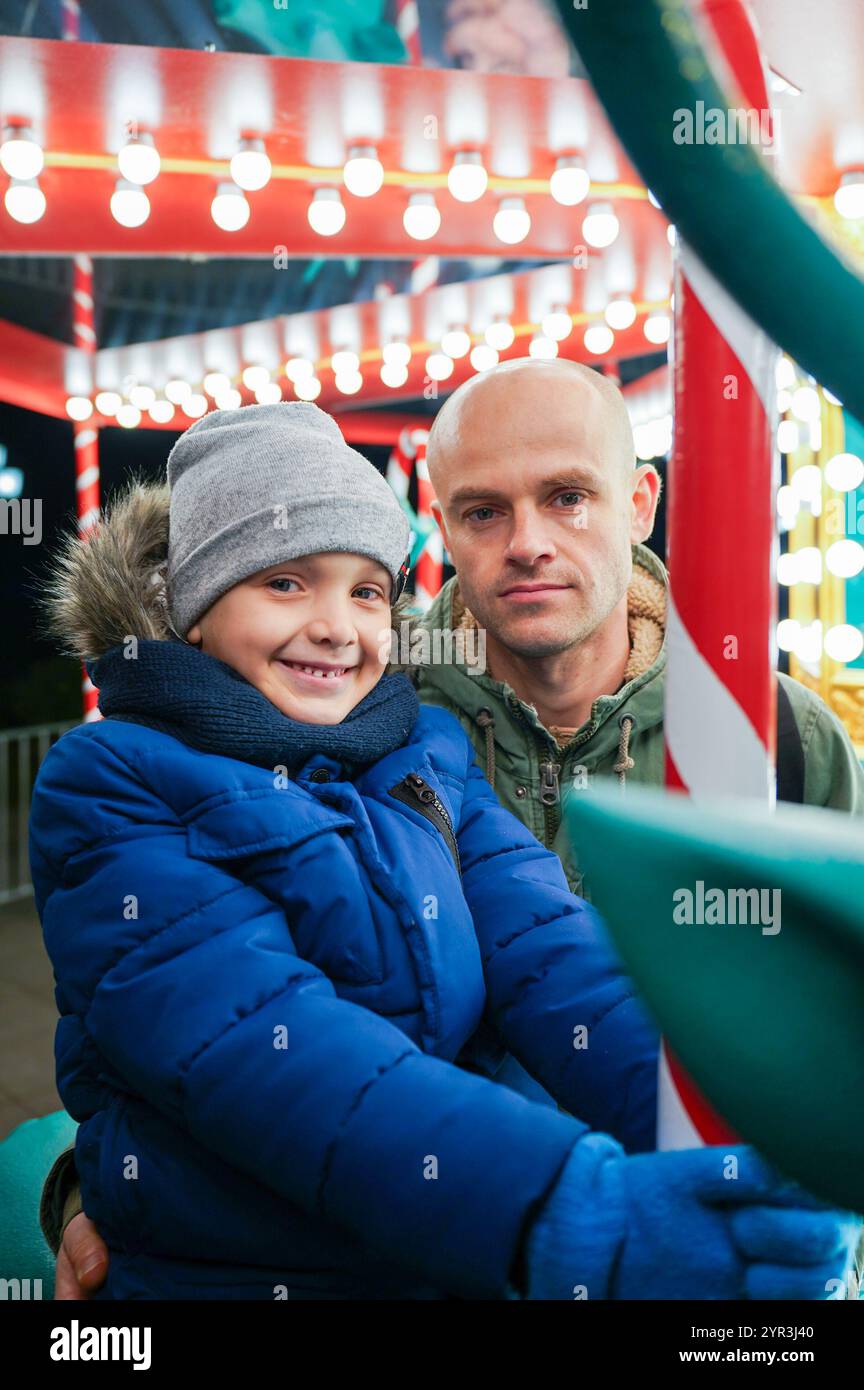 Family enjoying a carousel ride at a Christmas market on a winter night ...