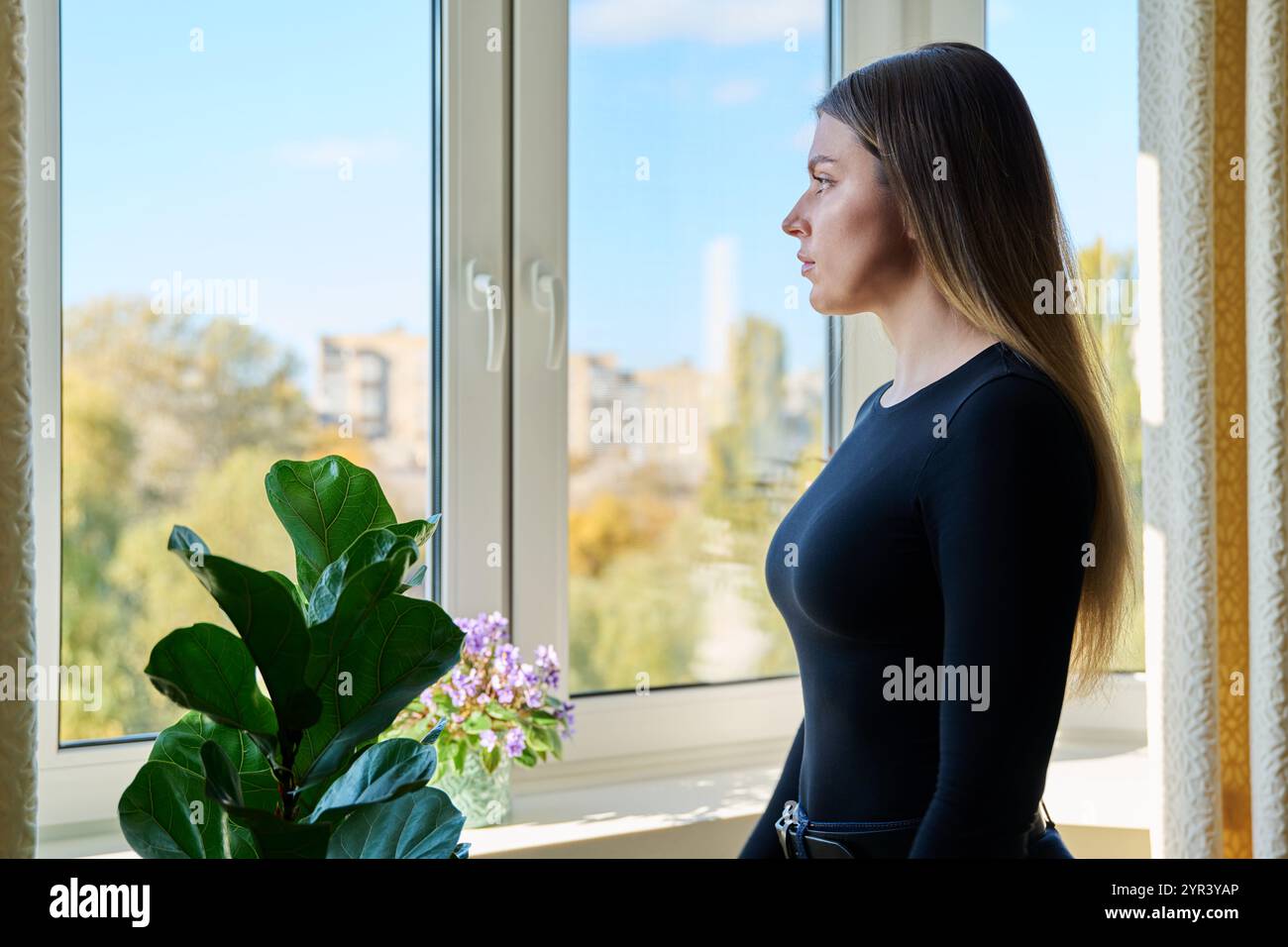 Serious young woman looking out the window Stock Photo - Alamy