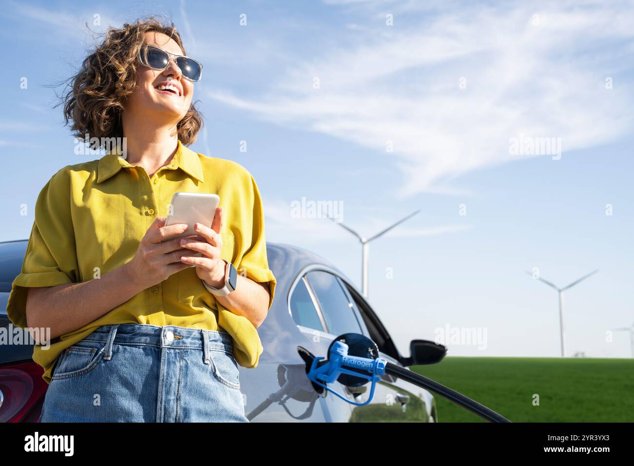 Woman with fueling hydrogen car. Refueling car with hydrogen fuel. Wind ...