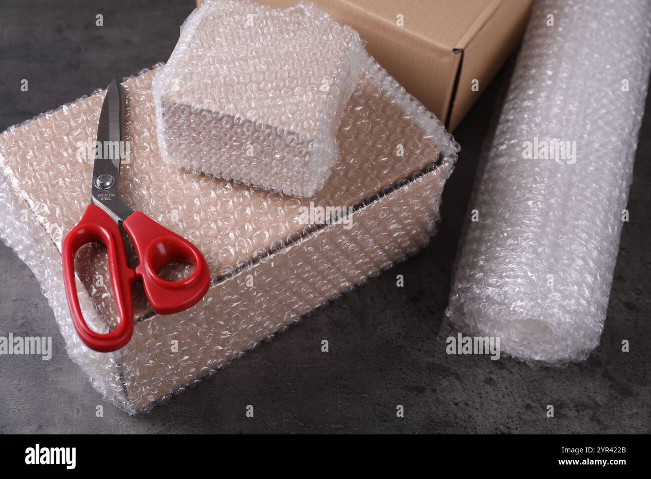 Cardboard boxes, bubble wrap and scissors on dark grey table Stock ...