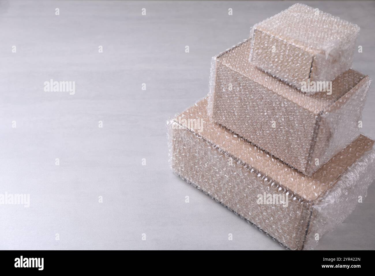 Cardboard boxes covered with bubble wrap on light grey table. Space for ...