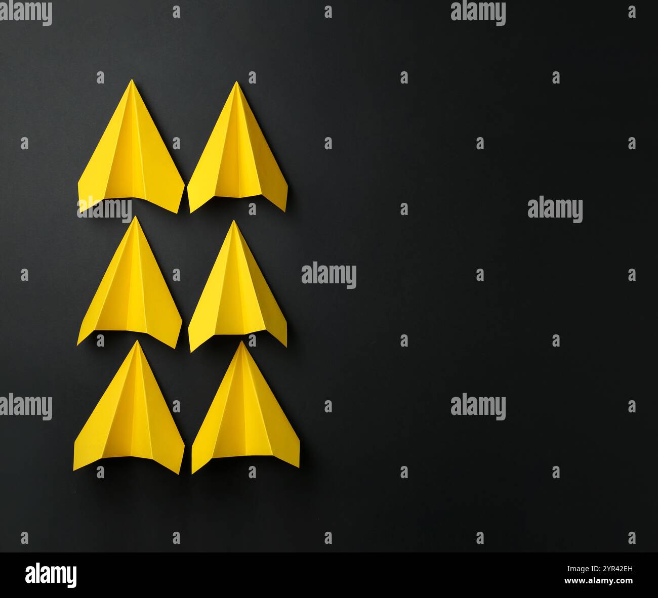 Handmade yellow paper planes on black background, top view. Space for ...