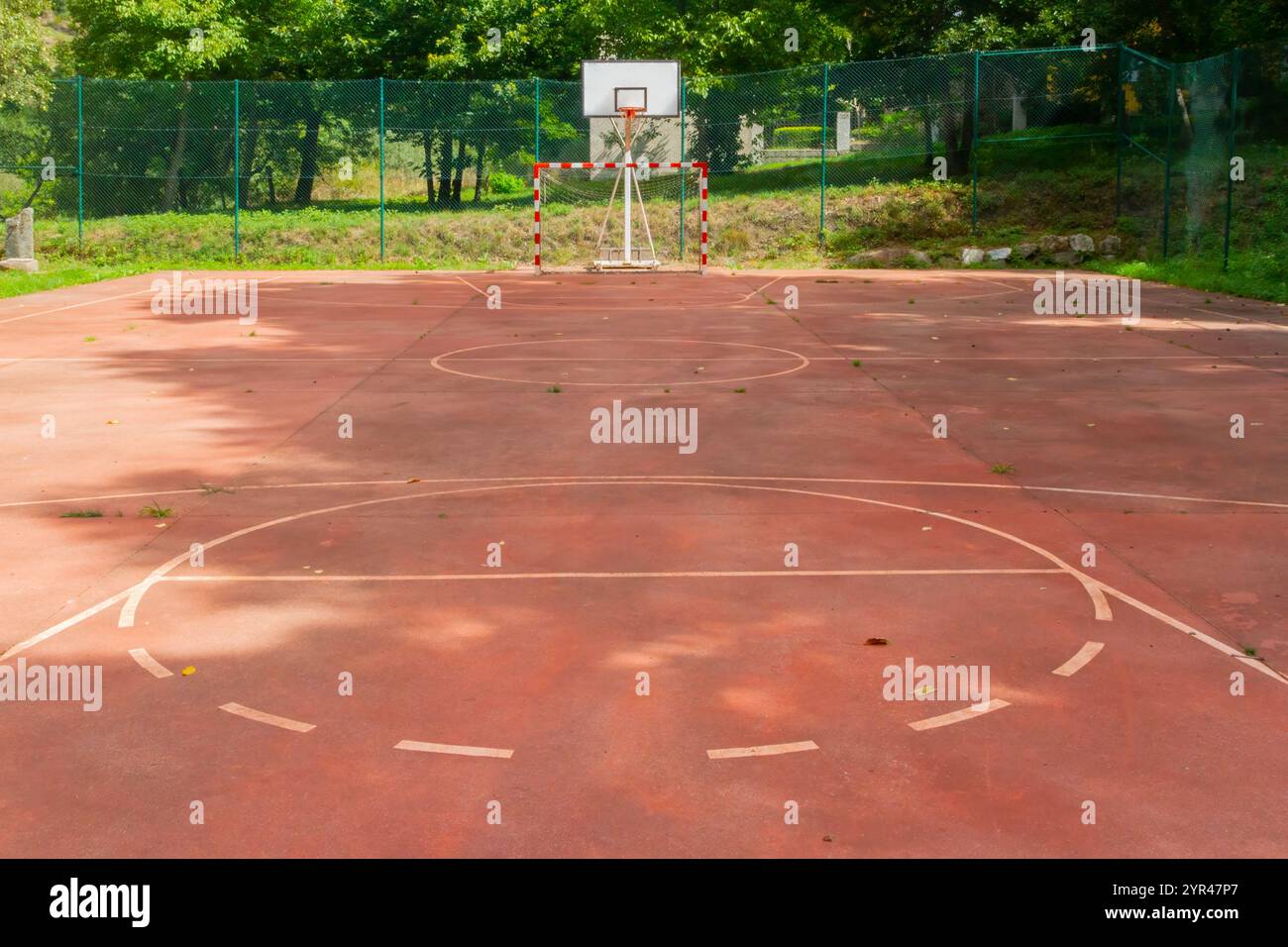 An outdoor basketball hoop towers overhead, its net swaying lightly ...