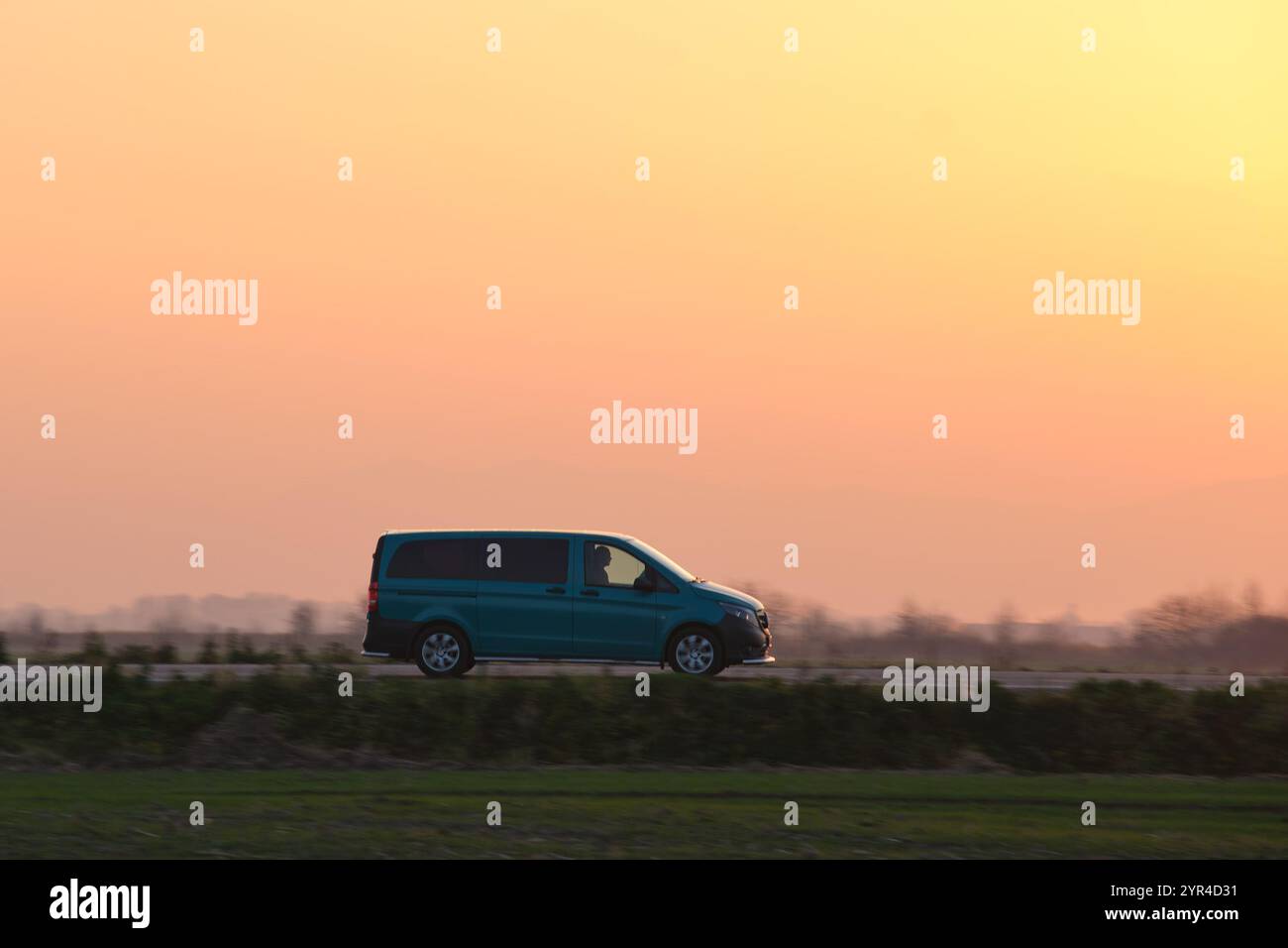 Passenger van driving fast on intercity road at sunset. Highway traffic ...