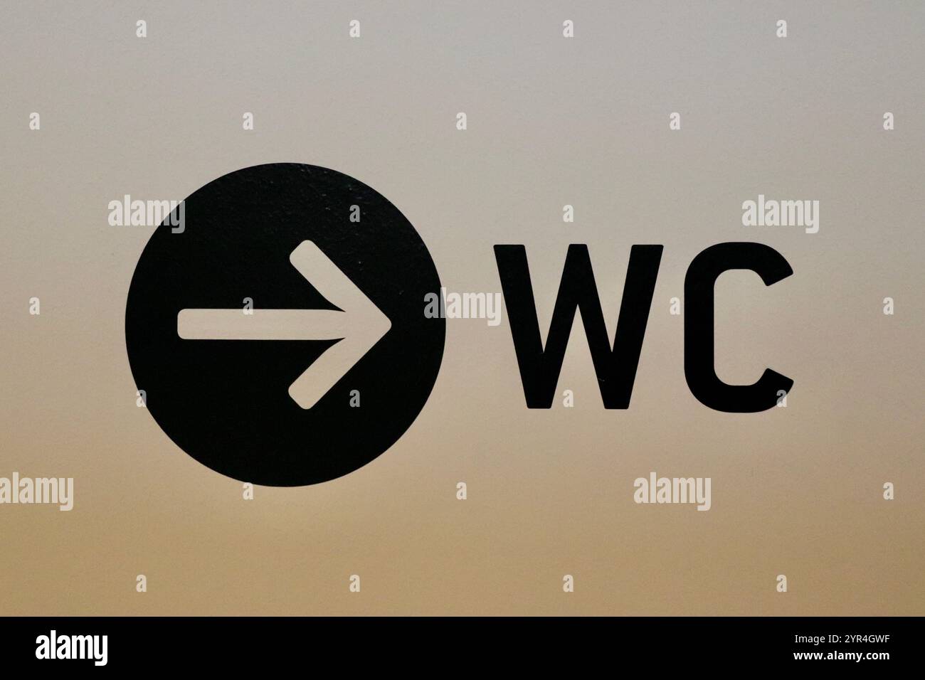 Minimalistic WC sign on white wall with an arrow pointing to the right ...