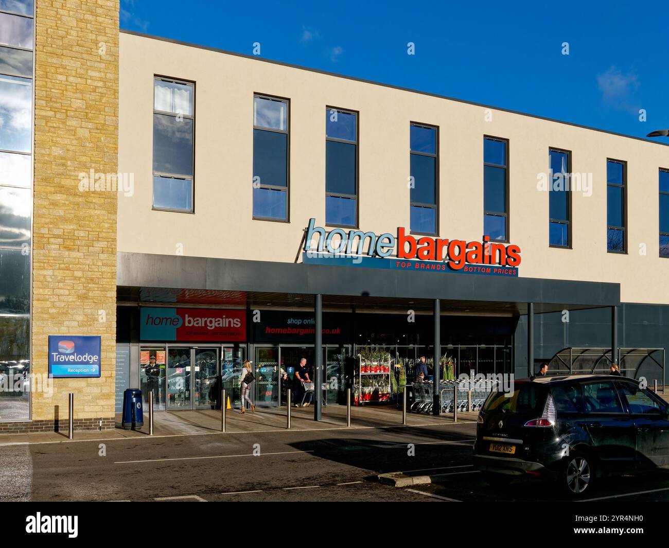 Exterior view of a Home Bargains retail store with parked cars and ...